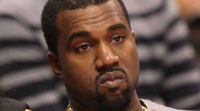 Kanye West takes shot at another pap outside police station